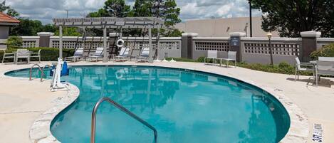 Piscina com pergolado, espreguiçadeiras e placa de proibição de saltos.