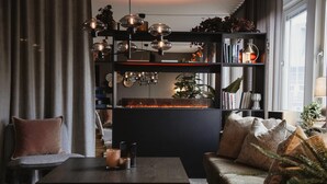 Uma sala de estar moderna com uma mesa de centro de madeira escura, um sofá de couro e um aparador preto com objetos decorativos e livros.