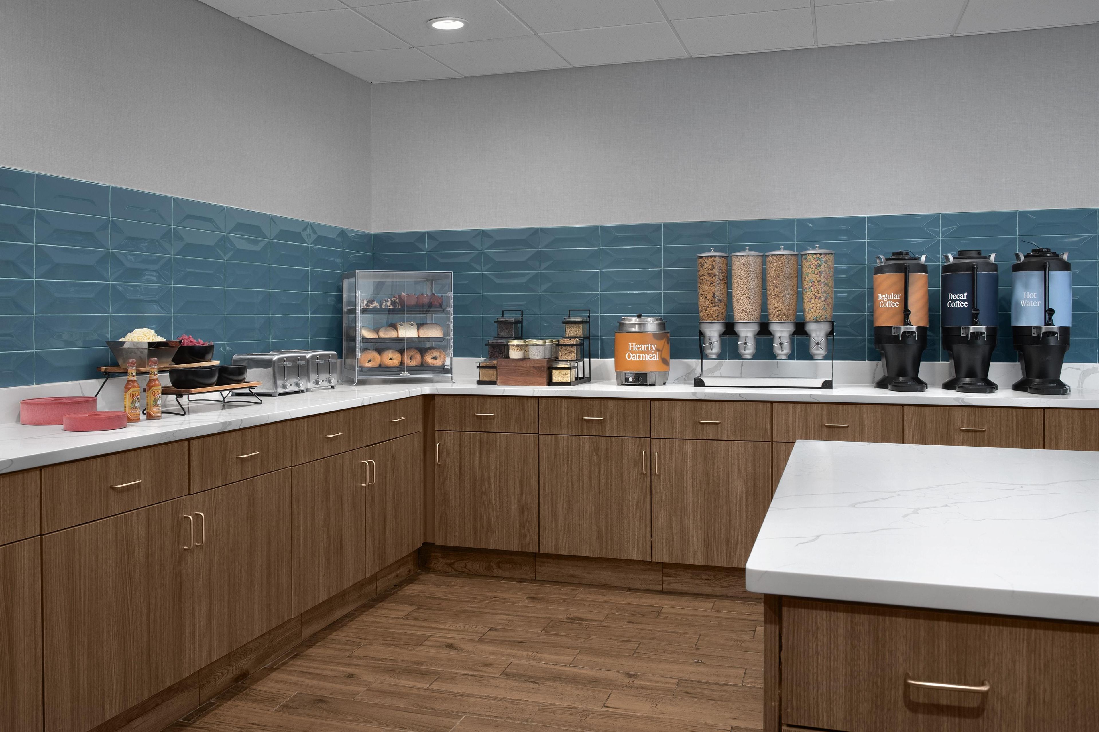 Uma cozinha moderna com armários de madeira, bancada de mármore e painel de azulejos azuis.