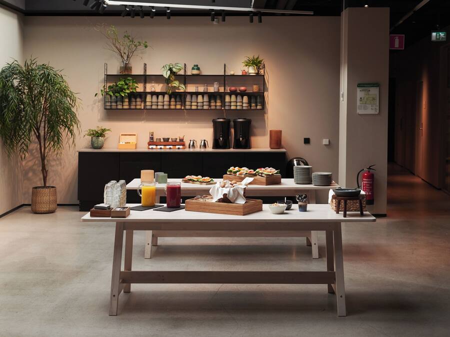 Mesa com itens de café da manhã e uma estação de café em um ambiente moderno.