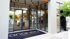 A entrada de um prédio moderno com portas de vidro e um tapete azul escuro com a inscrição "anainea Trophea Yachting Resort".