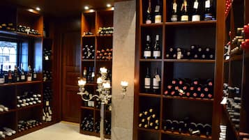 Adega com prateleiras repletas de garrafas de vinho e um candelabro.