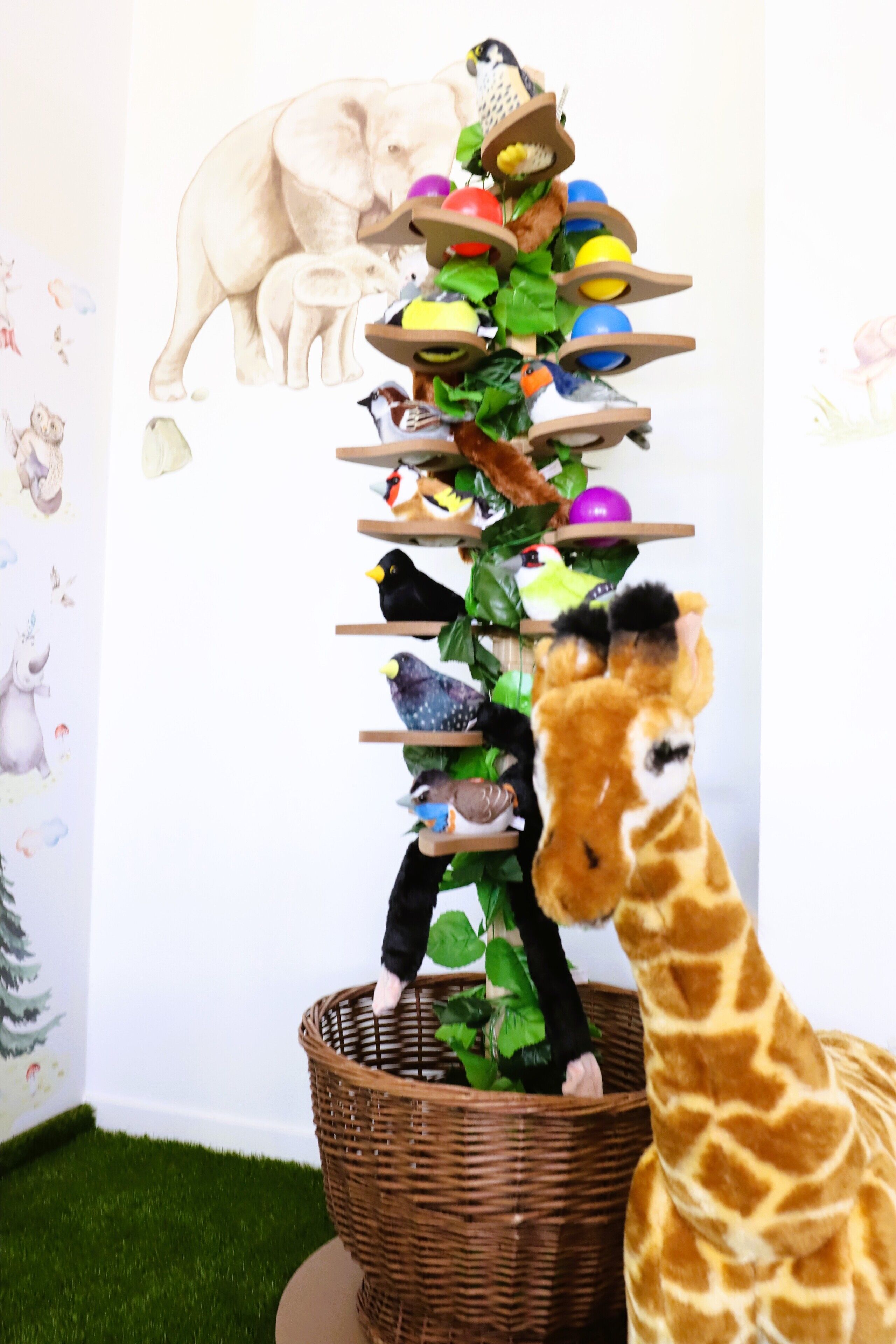 Um brinquedo de girafa ao lado de uma parede com um comedouro para pássaros.