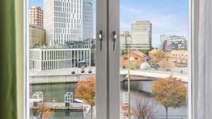 Vista pela janela de um edifício moderno, com um rio e pontes ao fundo.
