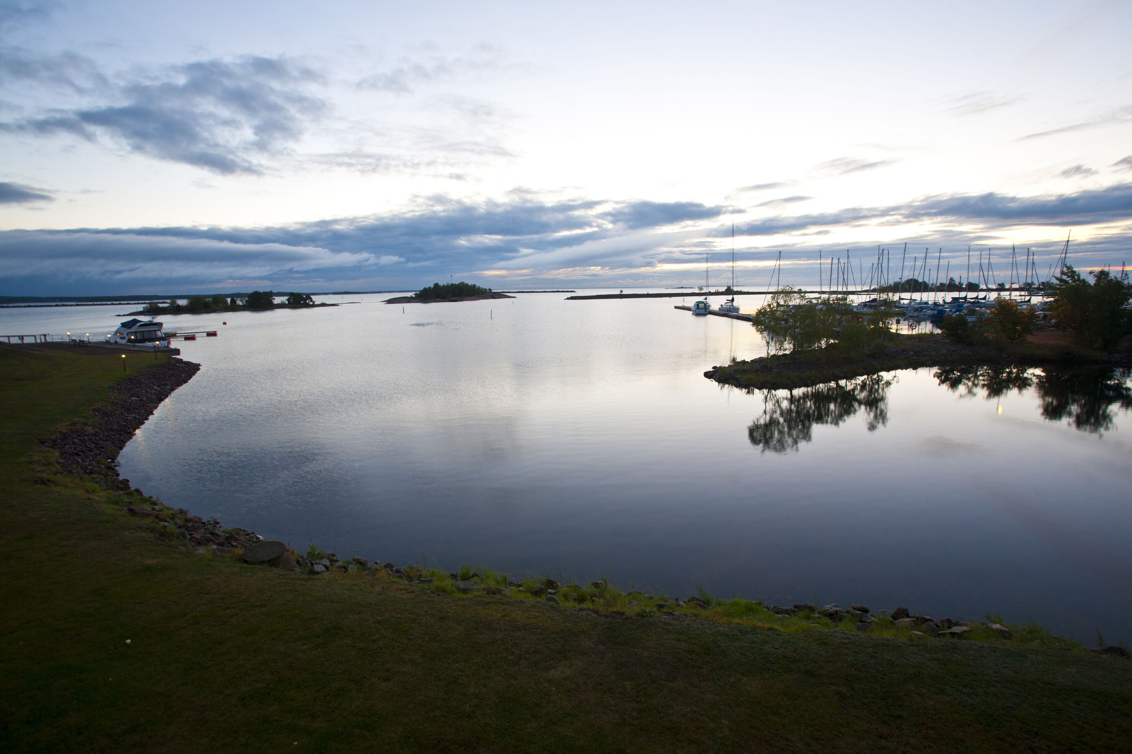 Um lago tranquilo com barcos, um cais e uma área gramada.