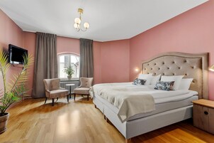 Quarto com cama, uma cadeira, televisão e planta em vaso.