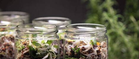 Vários potes de vidro cheios de salada sobre uma superfície de mármore.