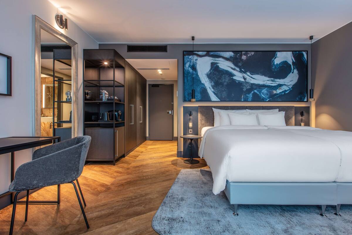 Um quarto moderno com uma cama grande, uma escrivaninha e um guarda-roupa.