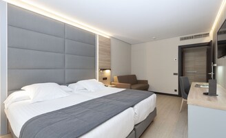 Quarto de hotel moderno com uma cama grande, uma escrivaninha e uma cadeira.