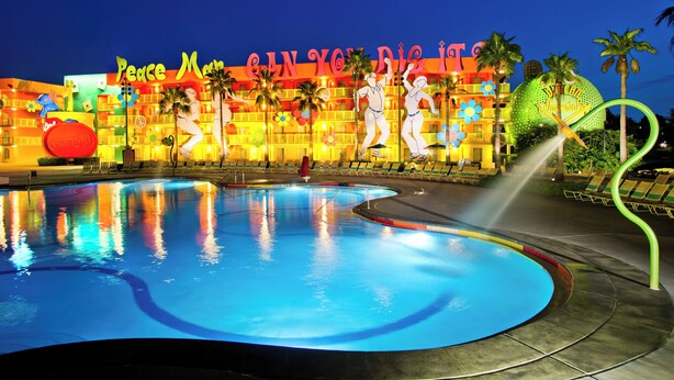 Um hotel com piscina grande, palmeiras e sinalização colorida.