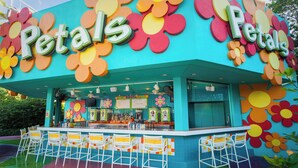 Um edifício colorido com tema floral, apresentando um espaço de bar com cadeiras e balcão.