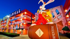 Um hotel com várias varandas, uma grande escultura em forma de barril e uma placa bem visível.