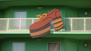 Um edifício com fachada verde e uma grande decoração em forma de sapato na varanda.