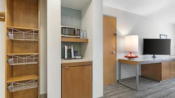 Quarto de hotel com cozinha compacta, micro-ondas, máquina de café e televisão.