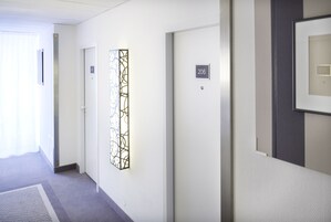 Um corredor com uma porta identificada com o número 206, um painel decorativo na parede e um quadro emoldurado.