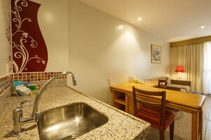 Cozinha com bancada de granito, pia de aço inoxidável e área de jantar com mesa e cadeiras de madeira.