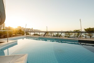 Piscina no terraço com paisagem urbana ao fundo.