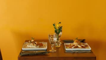 Uma mesa de jantar com dois pratos de comida, um vaso com flores e um quadro com peixes na parede.