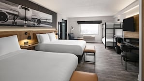 Quarto de hotel com duas camas, uma escrivaninha, uma cadeira, uma TV e uma janela grande.