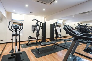 Uma academia com esteiras, aparelhos de musculação e colchonetes.