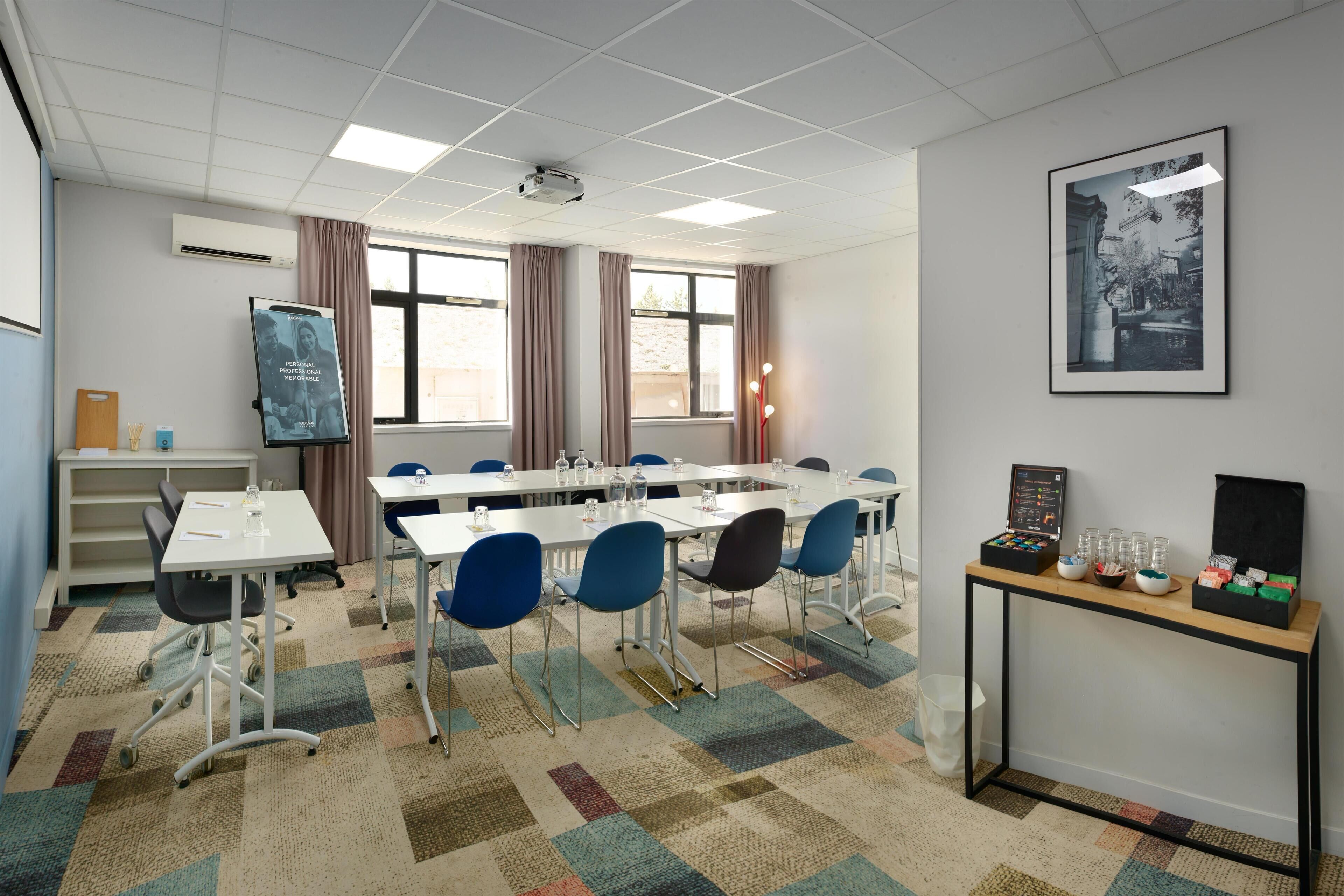 Uma sala de conferências com uma mesa comprida, cadeiras, um projetor e um quadro na parede.