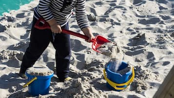 Criança brincando com areia na praia.