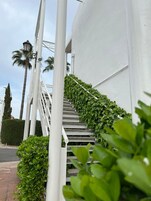 Uma escadaria com guarda-corpos brancos e folhagem verde.