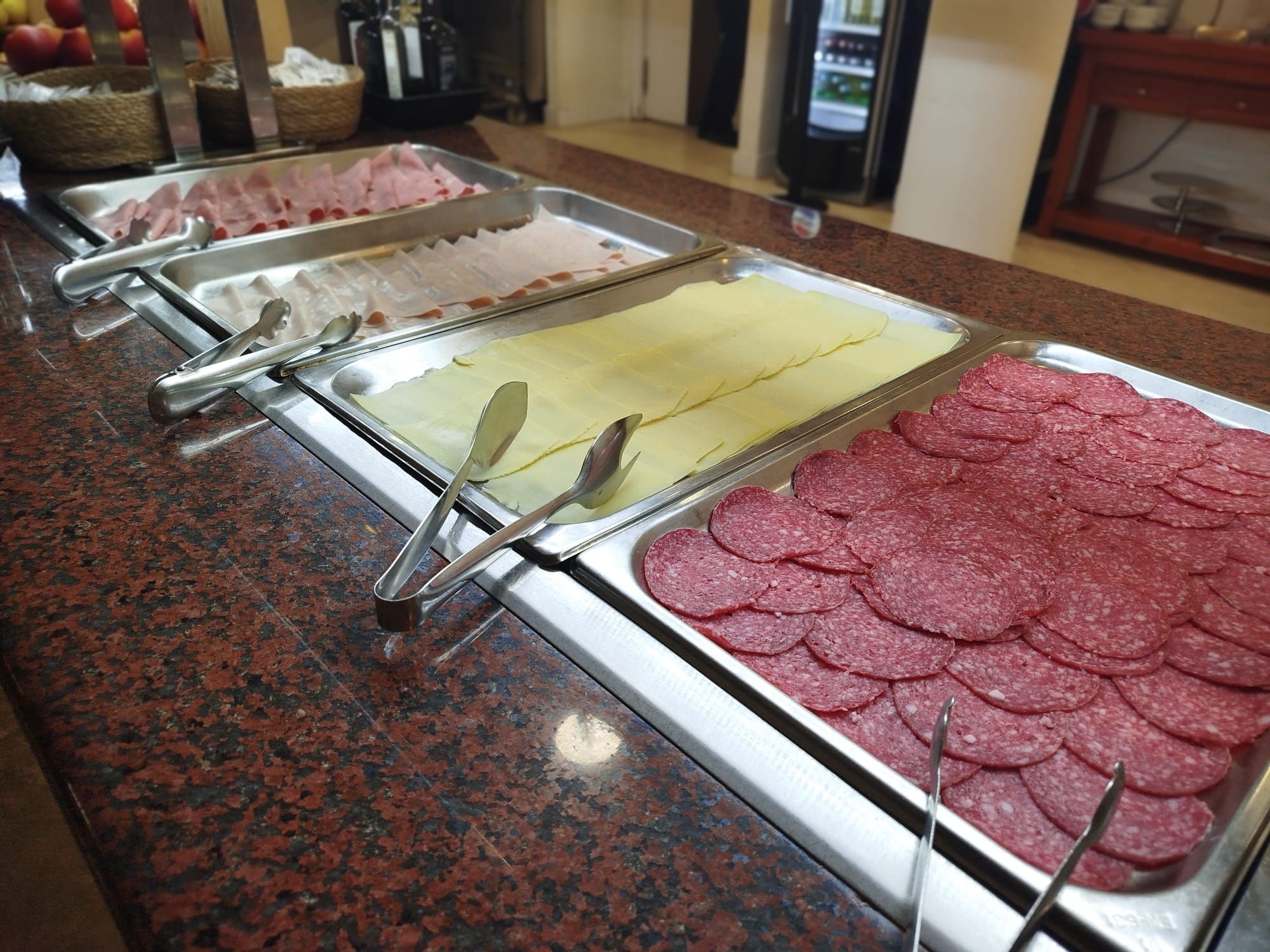 Buffet com diversos alimentos, incluindo carnes fatiadas e queijos.