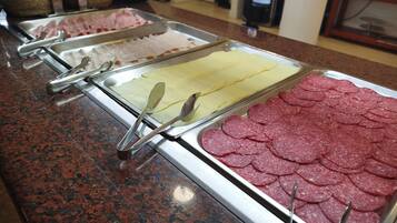 Buffet com diversos alimentos, incluindo carnes fatiadas e queijos.