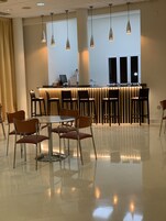 Uma área de bar moderna com piso polido, vários bancos altos e iluminação pendente.