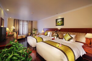 Quarto de hotel com duas camas, uma televisão, uma escrivaninha e uma cadeira.