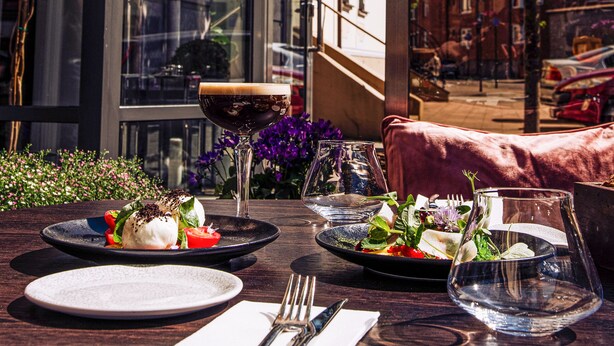 Restaurante chamado "City Port" com área externa para refeições, uma taça de vinho e mesa posta com pratos e talheres.