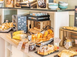 Vitrine de uma padaria com diversos tipos de pão, doces e potes de geleias.