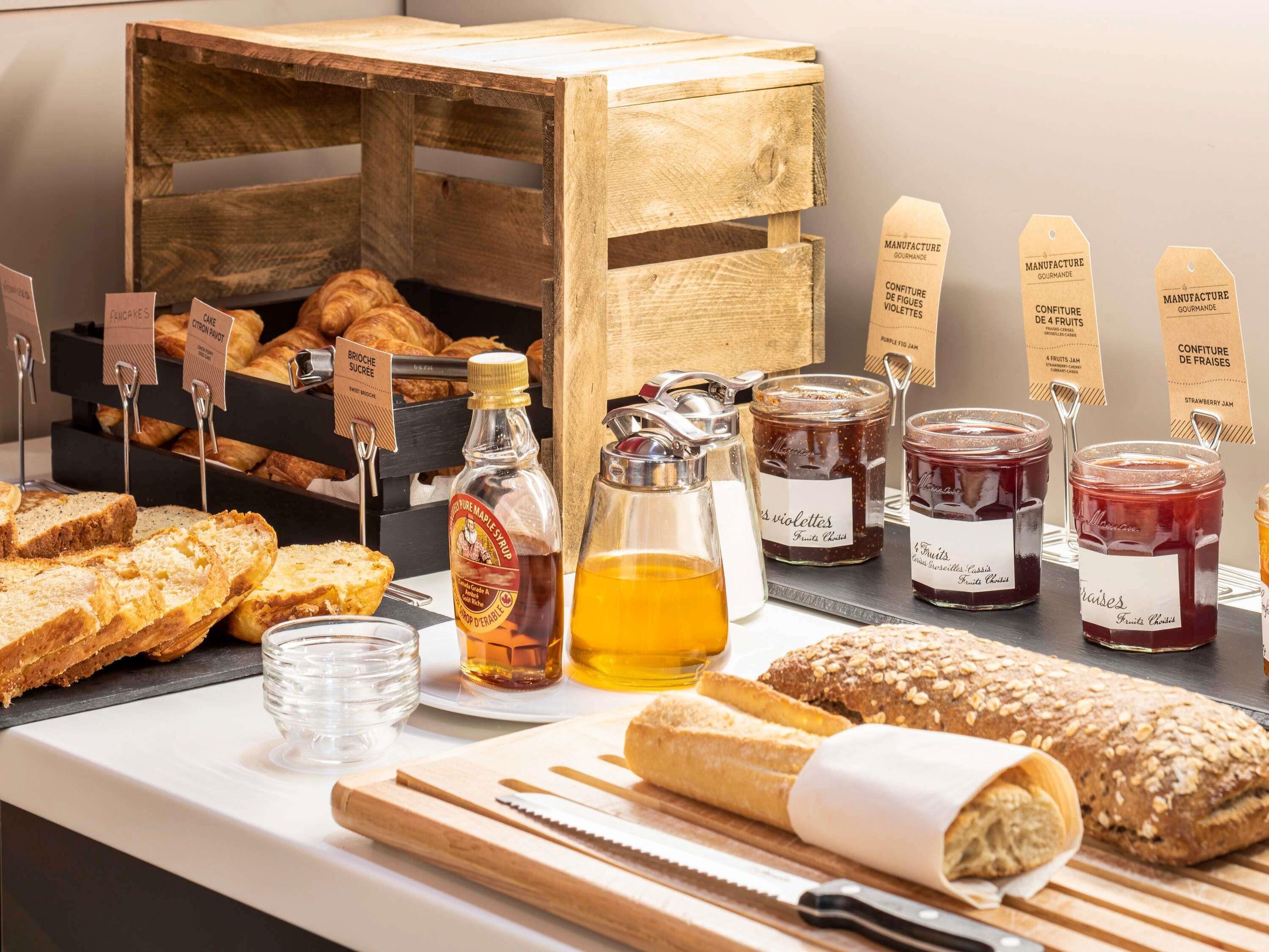 Um buffet de café da manhã com diversos pães, doces, geleias e mel.