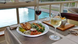 Uma mesa de jantar com um prato de comida, um copo de vinho tinto e um copo de vinho branco.