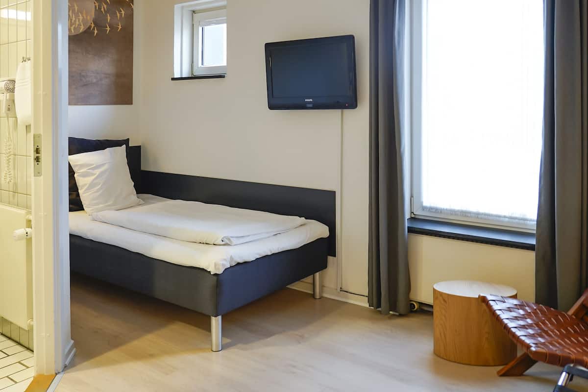 Um quarto moderno com uma cama, uma televisão, uma janela e uma cadeira.