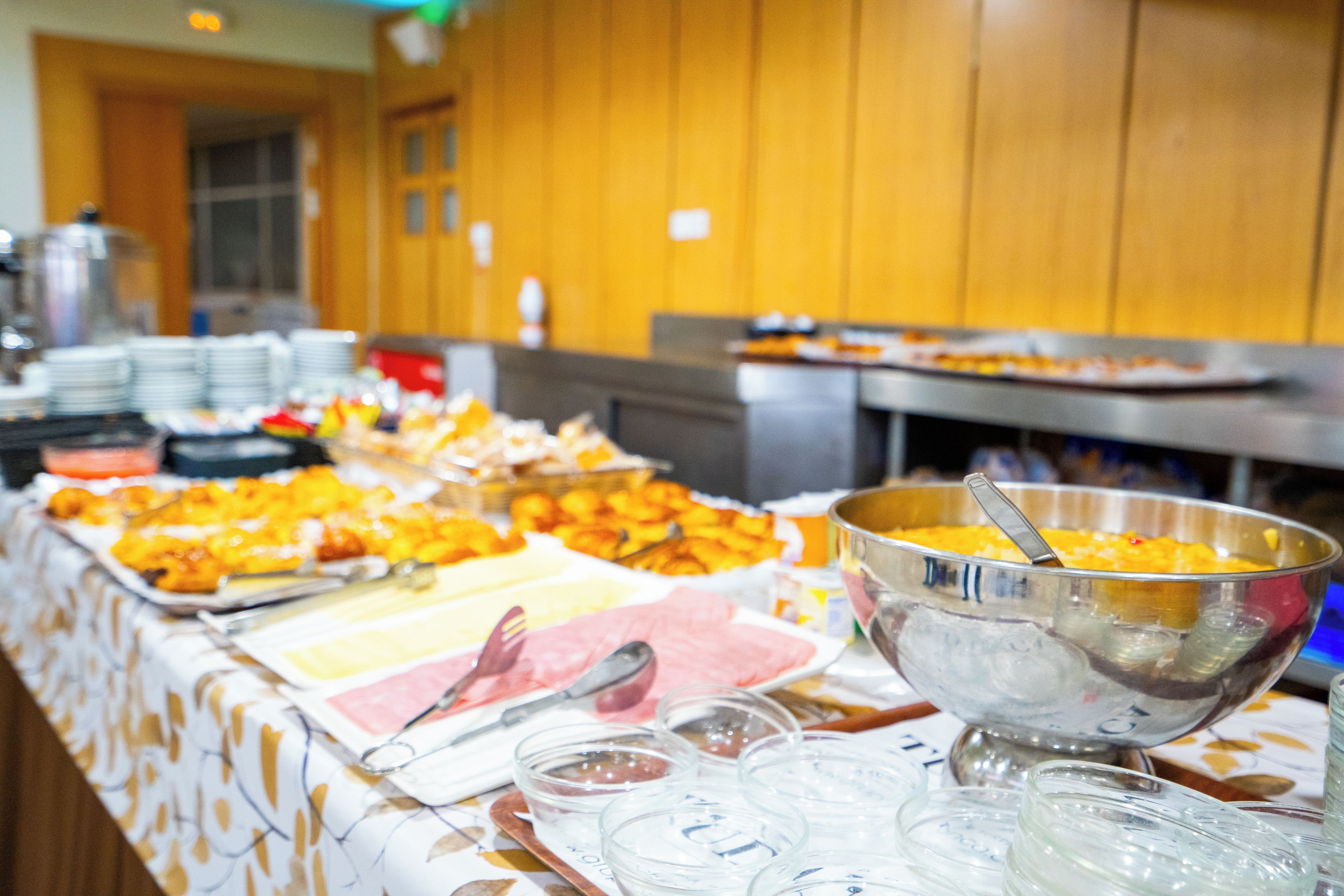 Disposição de buffet com diversos alimentos e utensílios de servir.