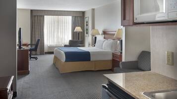 Quarto de hotel com cama, escrivaninha, cadeira, luminárias e micro-ondas.