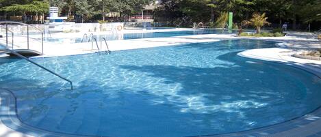 Uma piscina grande e límpida com um deck ladrilhado e um posto de salva-vidas.