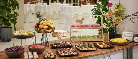 Uma mesa de buffet com diversos alimentos e um arranjo decorativo.