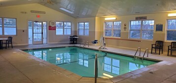 Piscina interna com água cristalina, cadeira de salva-vidas e placa de proibição de mergulho.