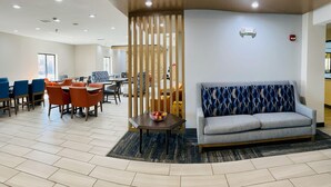 Um hall de hotel moderno com área de estar, balcão de recepção e um sofá estampado.