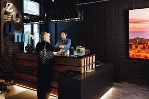 Uma mesa de recepção com design moderno, destacando um balcão de madeira e uma tela digital acima.