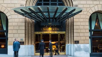Entrada do Hotel Omni, com design arquitetônico clássico, incluindo uma grande janela em arco e um toldo sobre a entrada.