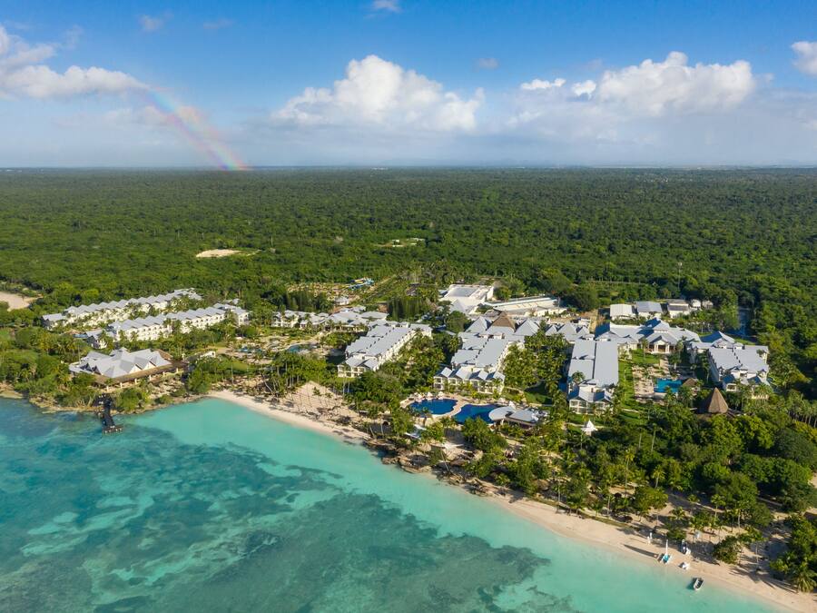 Vista aérea de um resort com vários edifícios, uma praia e águas turquesas cristalinas.