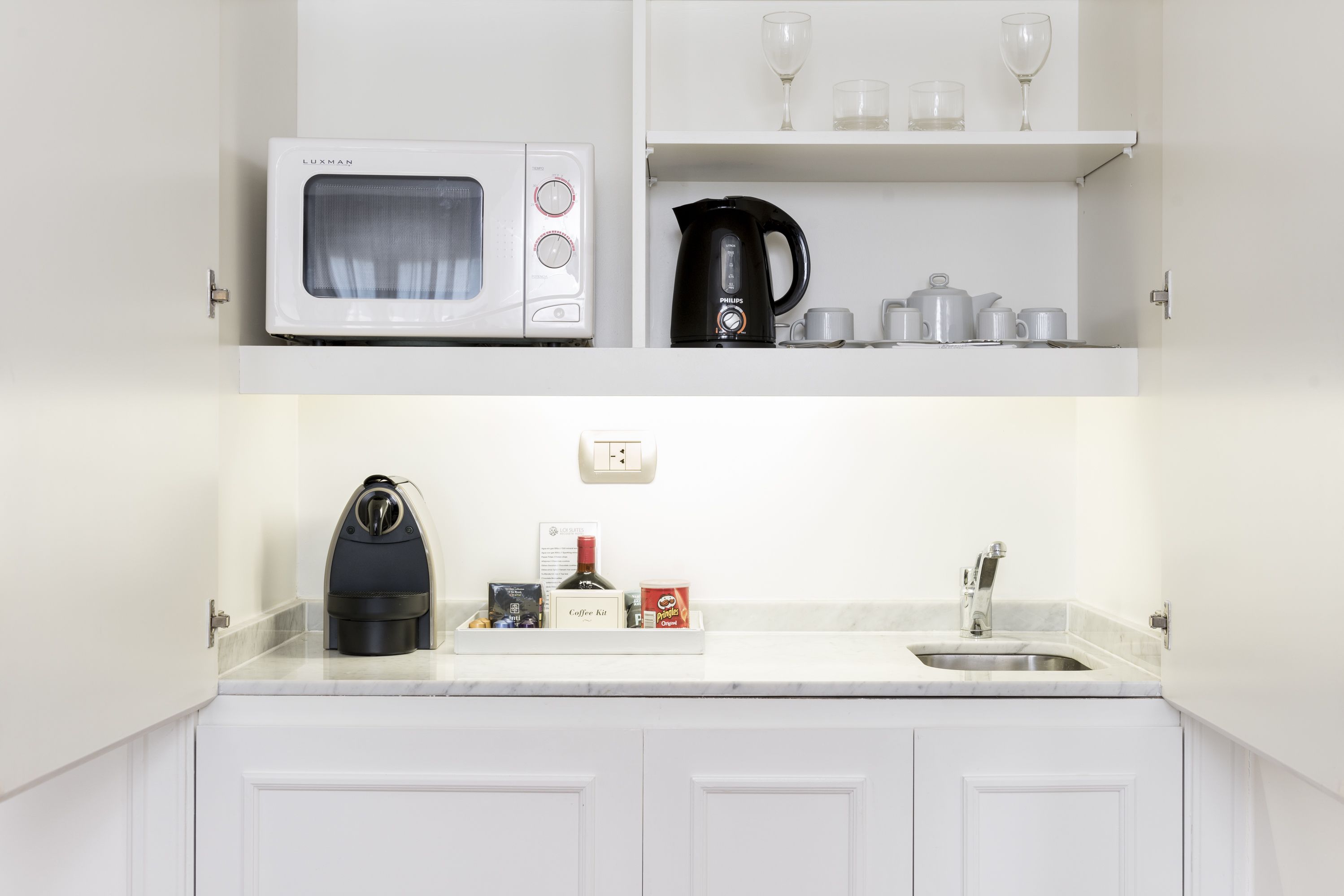Uma cozinha equipada com micro-ondas, cafeteira e espaço para café.