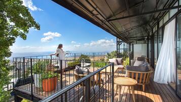 Varanda com vista para o mar, mobiliada com cadeiras e uma mesa, e um corrimão.