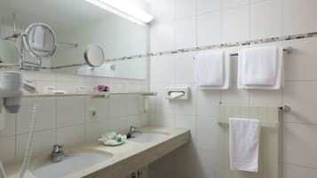 Casa de banho com duas pias, um espelho, um secador de cabelo e um porta-toalhas.