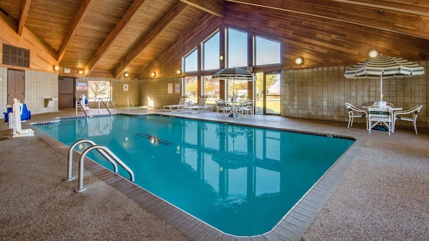 Piscina interior com teto de madeira, janelas amplas e espreguiçadeiras.
