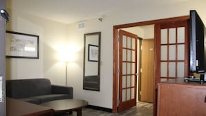 Quarto com sofá, mesa, televisão e aparador de madeira.